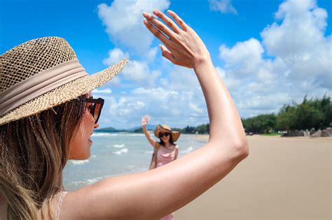 큰 모자와 선글라스를 들고 열대 모래 해변 푸른 바다에서 친구를 맞이하고 행복한 여성이 친구를 만나고 여름 휴가휴가에 인사를 하는 아름다운 아시아 여성 25 29세에 대한