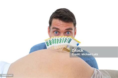 임신한 아기 범프 앞에서 기대하는 아버지는 얼굴 앞에 지폐를 들고 걱정스러운 표정을 짓는다 임신 마지막 달 39 주 흰색 배경입니다 밝은 샷 2명에 대한 스톡 사진 및 기타