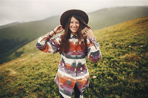 세련 된 여행자 Hipster 소녀 모자 배낭과 바람 머리를 들고 산 구름 속에서에 웃 고 텍스트를 위한 공간입니다 놀라운 대기 순간입니다 여행과 방황 개념 개념에 대한