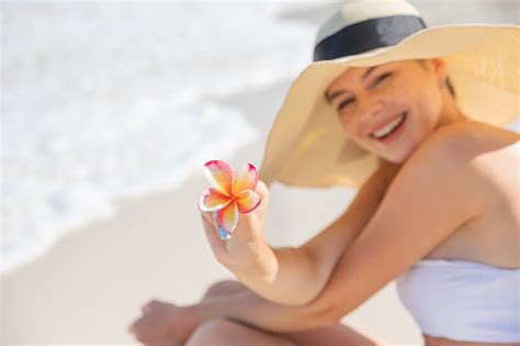 젊은 여자가 해변에서 쉬고 있습니다 행복한 섬 라이프스타일 모자를 쓰고 꽃을 들고 해변에 앉아 있는 소녀 초점이 맞는 꽃 25 29세에 대한 스톡 사진 및 기타 이미지