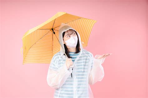 진지한 아시아 여성의 사진은 바이러스로부터 자신을 보호하고 질병을 잡기 위해 의료용 마스크를 쓰고 분홍색 배경에 우산 아래 서 있다 가을과 질병 개념 비에 대한 스톡 사진