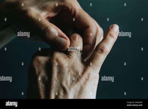 A Pair Of Old Hands Grabbing A Jewelry Ring On The Finger Over A Dark