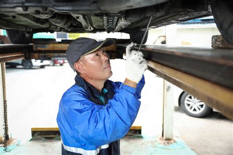 Stock Foto „동네 카센터에서 리프트에 올려진 자동차 하체를 점검하는 엔지니어 Adobe Stock