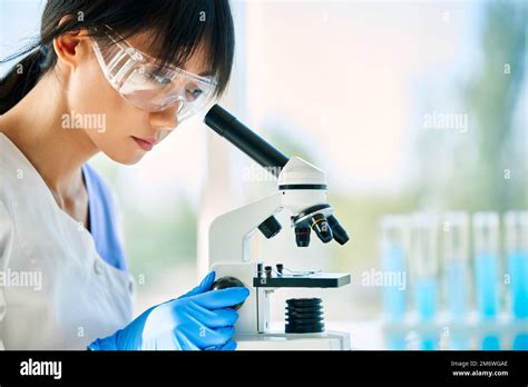 Portrait Of Asian Scientist Looking Through A Microscope Working On Medical Research In Modern