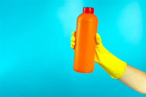 고무 보호 장갑을 낀 청소부의 손이 배경에 세척 화학 물질이 묻은 병을 들고 있습니다 상업용 청소 회사 봄철 정기 청소 텍스트 또는 로고를 위한 공간입니다 가사 집안일에