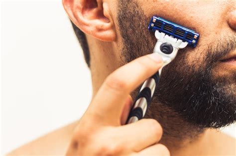 Premium Photo Close Up Of Young Man Shaving Beard Against White