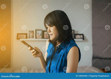Asian Woman Using Mobile Phone And Searching Social Network In Bedroom
