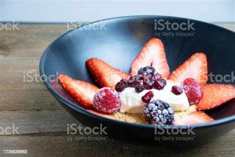 얇게 썬 딸기 쿠키 크럼블 휘핑 크림 석류 씨앗 블랙베리 딸기로 채워진 검은 색 메이트 접시의 측면보기 0명에 대한 스톡 사진