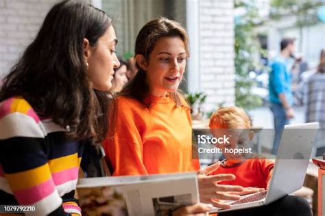 두 젊은 여자와 카페 또는 레스토랑에서 노트북 보고 어린 소년 2명에 대한 스톡 사진 및 기타 이미지 2명 가리키기 가족 Istock