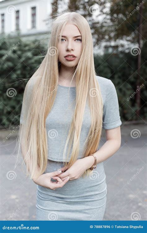 Portrait Of A Beautiful Cute Girl With Long Blond Hair In A Gray Suit