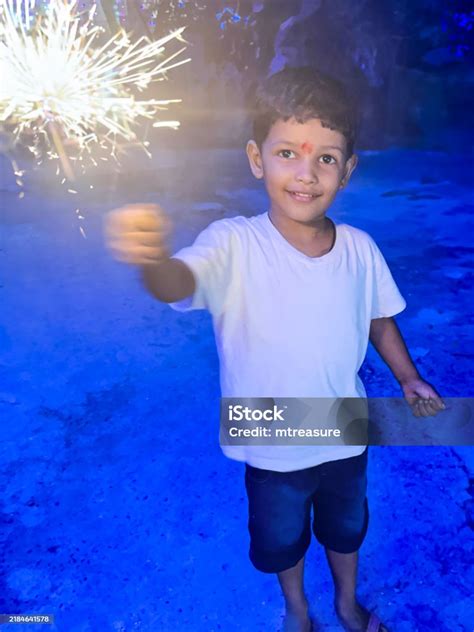 캐주얼 한 옷 티셔츠 및 반바지를 입은 어린 인도 소년이 디왈리를 축하하기 위해 불을 붙인 폭죽을 들고 있으며 폭죽과 불꽃 놀이로 빛의 힌두교 축제 디 왈리 축제 2 3
