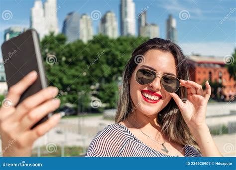 Smiling Young Woman Playing With Her Glasses And Taking A Selfie On A