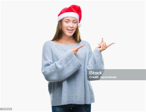 젊은 아름 다운 백인 여자 웃 고 옆에 두 손과 손가락으로 가리키는 카메라 보고 격리 된 배경 위에 크리스마스 모자를 쓰고 가리키기에 대한 스톡 사진 및 기타 이미지