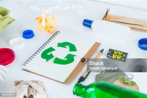 흰색 나무 바탕에 금속 플라스틱 오래 된 종이 유리 제품으로 재활용 쓰레기와 재사용 가능한 폐기물로 둘러싸인 녹색 에코 기호로 종이 노트북을 재활용 합니다 선택적 초점 0