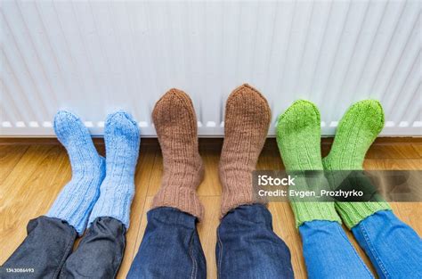 차가운 집에서 히터 앞에서 차가운 발을 따뜻하게 하는 니트 온울 양말을 입은 사람들 에너지 효율에 대한 스톡 사진 및 기타