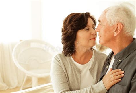 Mature 60 Year Old Couple Hugging While Sitting On The Bed In The
