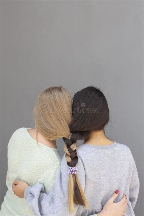 Two Girls With Different Color Of Hair Are Standing And Hugging Each