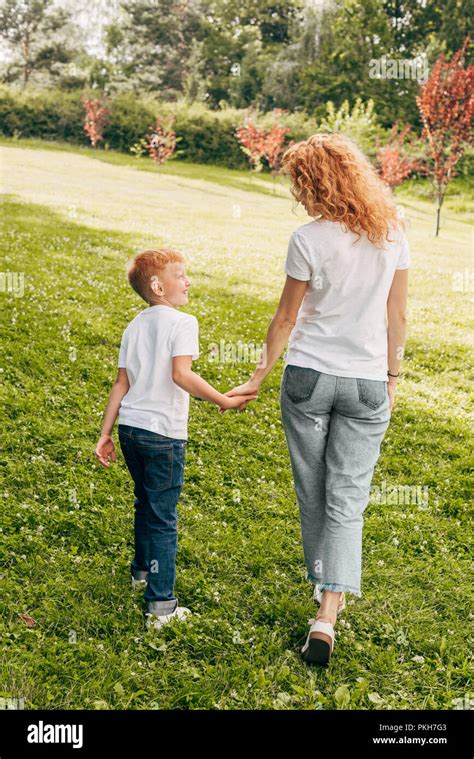Back View Of Happy Mother And Son Holding Hands And Walking Together In