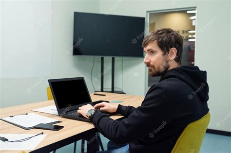 Premium Photo Young Man Working On Laptop Sitting At His Workplace In Coworking Office Side View