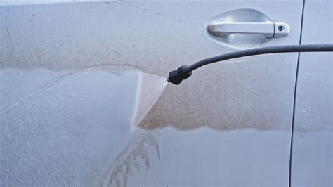 따뜻한 물과 섀시 샴푸로 압력 세탁기를 사용하여 셀프 사용 세차장에서 흰색 차량 문에서 먼지와 진흙을 씻어 활성 거품의 안개와 비누 거품을 만드는 세차장에 대한 스톡 사진