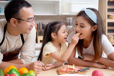 부엌에서 아버지 어머니 딸과 함께 행복한 가족 딸이 집에서 함께 사과 과일을 먹이고 엄마 아빠 아이는 유대감과 관계 생활 방식과 영양 개념을 가지고 있습니다 3 명에 대한