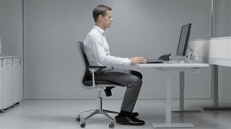 A Man Sitting At A Desk Working On A Computer In A Modern Office Environment Premium Ai