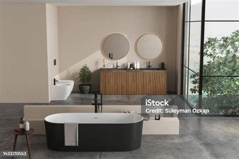 베이지 색 벽이있는 현대적인 욕실 인테리어 이중 거울이있는 대리석 분지 검은 욕조 및 회색 콘크리트 바닥 현대적인 가구가있는 미니멀리스트 욕실 나무와 가로 보기가 내려다 보