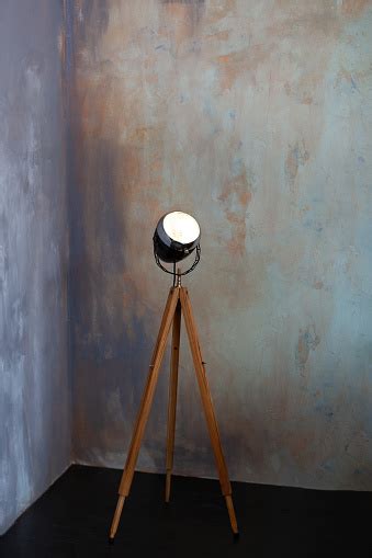 객실 내 삼각대에 세련된 램프 삼각대 빛 프로젝터 장식용 라이트 프로젝터는 회색 콘크리트 벽에 서 있습니다 로프트 거실 인테리어