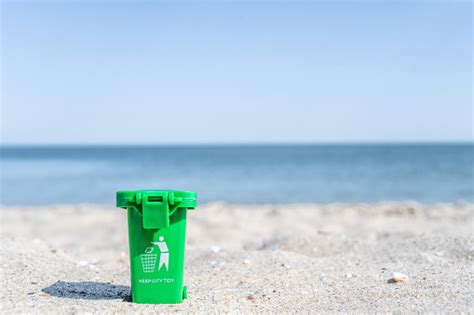 모래 해변에서 재활용에 적합한 종이 플라스틱 유리 및 유기 폐기물로 녹색 색의 쓰레기통이 있습니다 쓰레기 분리 쓰레기 선별 깨끗