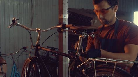 테마 중소 기업 자전거 수리 안전 고글 장갑과 앞치마를 착용 젊은 백인 갈색 머리 남자는 수리및 작업장 차고에서 자전거를 조정하기 위해 손 도구를 사용 강철에 대한 스톡