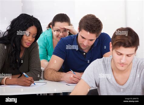 Female College Babes Trying To Cheat From Male Classmate During Test In Classroom Stock Photo