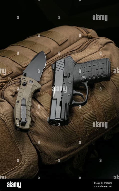 A Small Modern Pistol And Penknife On A Brown Military Backpack Self