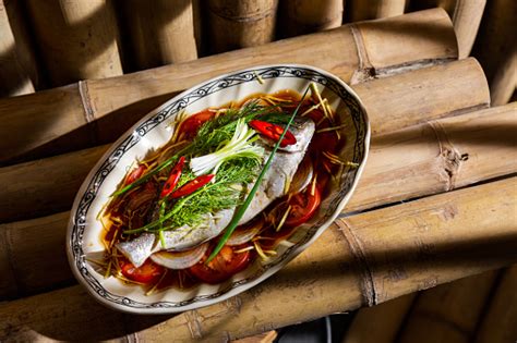 튀긴 생선 칠리 페퍼 토마토 소스 양파 딜 고구마 조각을 대나무 줄기로 만든 테이블 위의 접시에 담은 샐러드 감자 요리에 대한