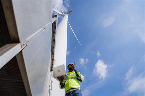 노란 재킷을 입은 남자가 풍력 터빈 옆에 서서 휴대전화로 통화하고 있다 전기 엔지니어 환경 에너지 깨끗한 지속 가능 풍력 터빈