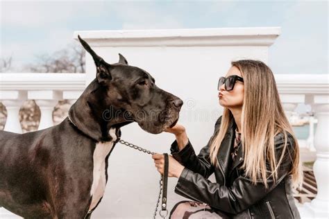 A Woman Walks With Her Great Dane In An Urban Setting Enjoying The Outdoors And The Company Of