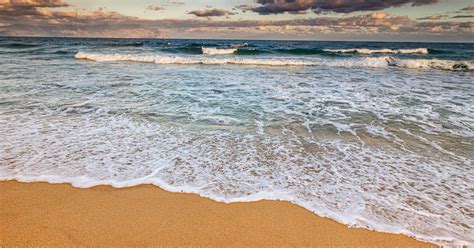 만조 때 들어오는 푸른 파도가 있는 목가적인 바다 모래 해변의 광각 전망 해질녘에 바람이 불고 폭풍우가 치는 날씨 여행과 휴가의 배경 사진 Unsplash의 바다