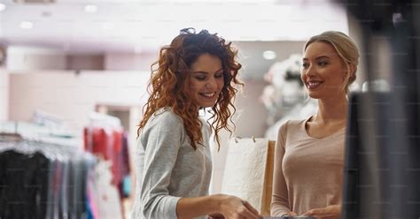 여성 상점 매니저가 옆에 머무르는 동안 드레스 쇼룸의 등록부에 신용 카드로 지불하는 쾌활한 젊은 여성의 허리 위로 초상화 사진 Unsplash의 기쁨 이미지