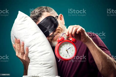 빨간 티셔츠와 수면 마스크를 머리에 시계시계와 베개를 들고 놀란 남자 라이프스타일 및 취침 시간 개념 T 셔츠에 대한 스톡 사진