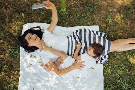 행복 영 어머니 복용 Selfie 잔디에 웃 고 딸과 함께 피크닉 동안 거짓말의 보기 위의 야외 공원에서 젊은 가족 복용 Selfie입니다 어머니 육아와 아동 개념입니다