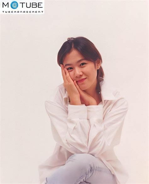 A Woman Sitting On The Ground With Her Hand Under Her Chin And Looking