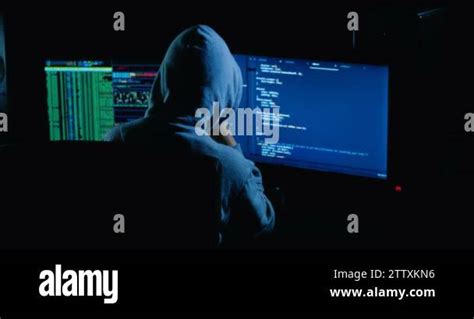 acker in hood cracking code using laptop and computers from his dark