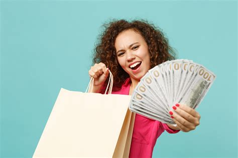 쇼핑 달러 지폐에 돈의 팬 파란색 청록색 배경에 고립 된 현금 돈 후 구매와 패키지 가방을 들고 재미 있는 아프리카 소녀 사람들 라이프 스타일 개념입니다 복사 공간을 모의