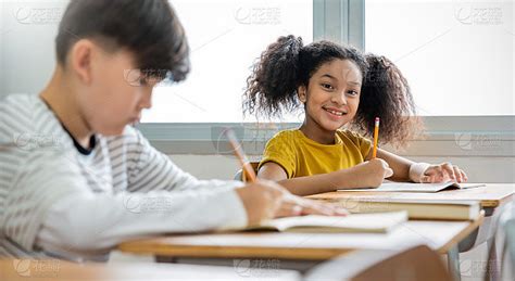 小学生在教室课桌上写字的肖像。学生非洲女孩在小学做测试。孩子们在教室里写笔记。教育知识横幅