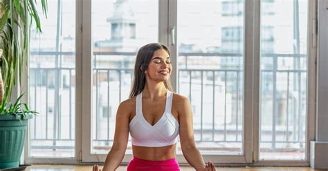 요가를 연습하는 젊은 매력적인 웃는 여자 하프 로터스 운동에 앉아 Ardha Padmasana 포즈 운동 운동복 착용