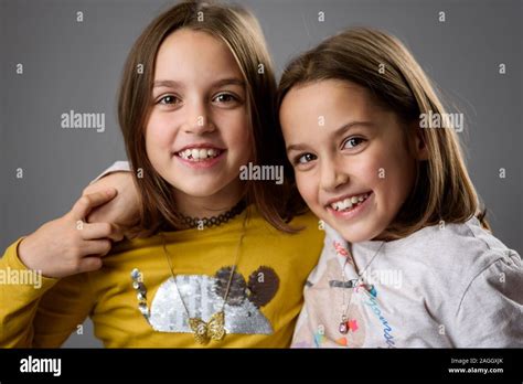 Identical Twin Girls Sisters Are Posing For The Camera Happy Twin