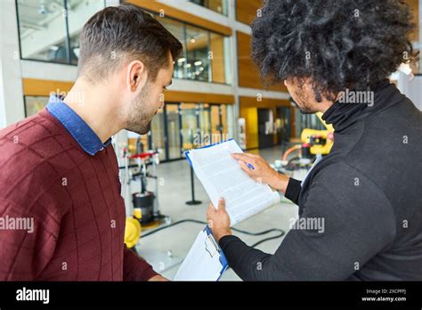 Two Engineers Review Documentation And Discuss Robotics And Automation