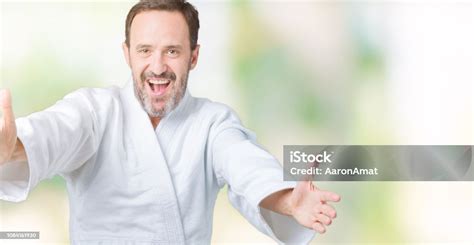 잘생긴 중 년 수석 사람 포옹에 대 한 두 팔을 벌려 웃 고는 카메라를 보고 하는 고립 된 배경 위에 균일 한 기모노를 입고