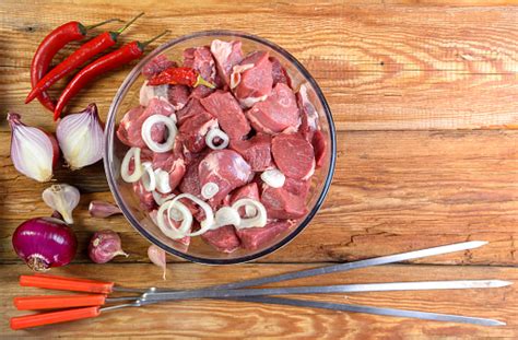 뼈없는 양고기 스테이크 얇게 썬 양파 유리 그릇에 고기 바질 칠리 페퍼 나무 테이블에 양념장 상단 보기 클로즈업 고기에 대한