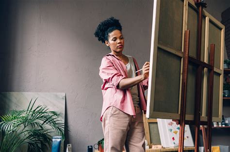 핑크 셔츠를 입은 아름다운 아프로 여성 아티스트 그녀의 홈 스튜디오에서 캔버스에 그림 색칠한 이미지에 대한 스톡 사진 및 기타 이미지 색칠한 이미지 예술 취미