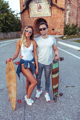 도시에서 여름에 젊은 부부는 스케이트 보드 및 Longboards을 보유 하고있다 흰색 수영복 Bodysuit T셔츠와 청바지에 남자 여자 시 휴식 젊음 오락의 개념입니다